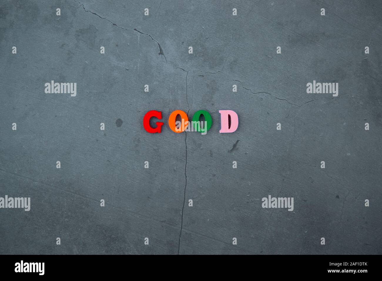 The multicolored good word is made of wooden letters on a grey ...