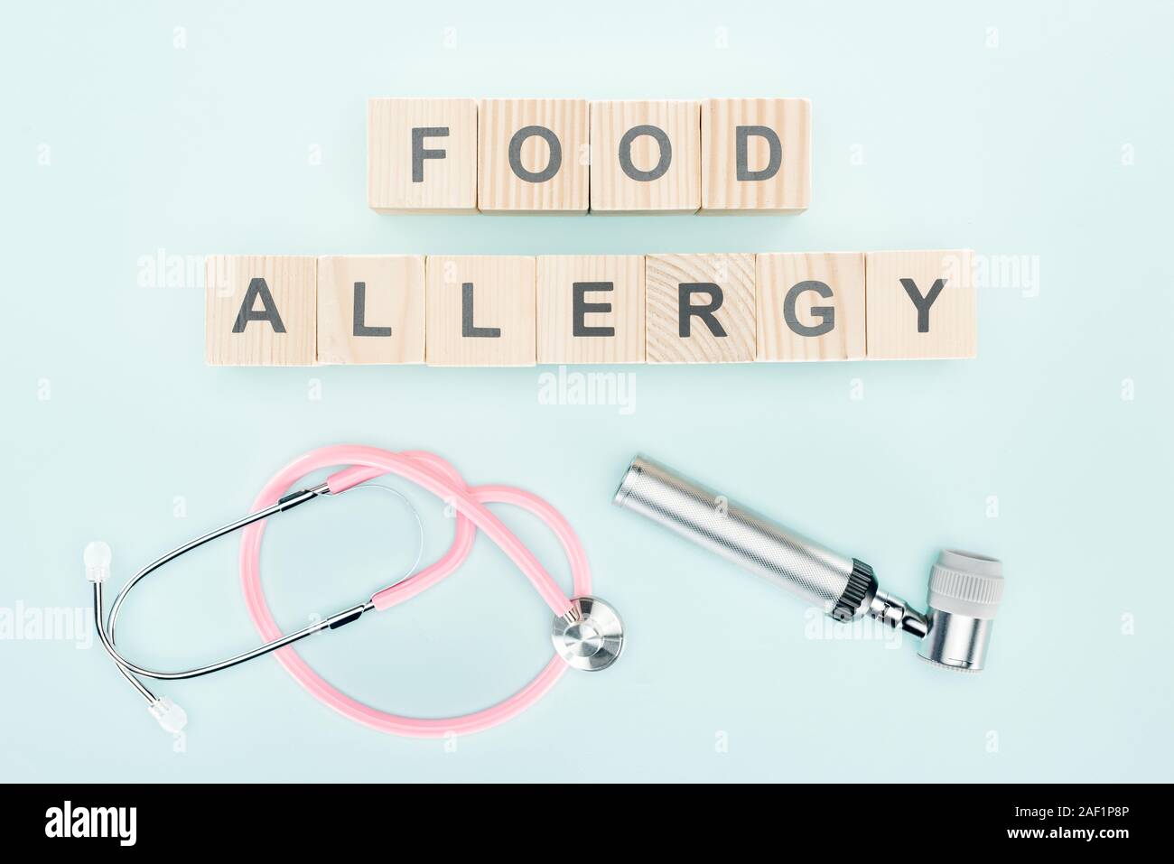 top view of pink stethoscope near wooden blocks with food allergy ...