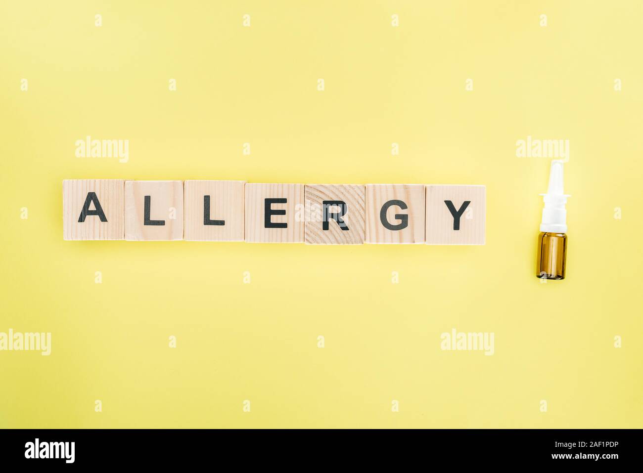 top view of wooden blocks with allergy lettering near nasal spray ...