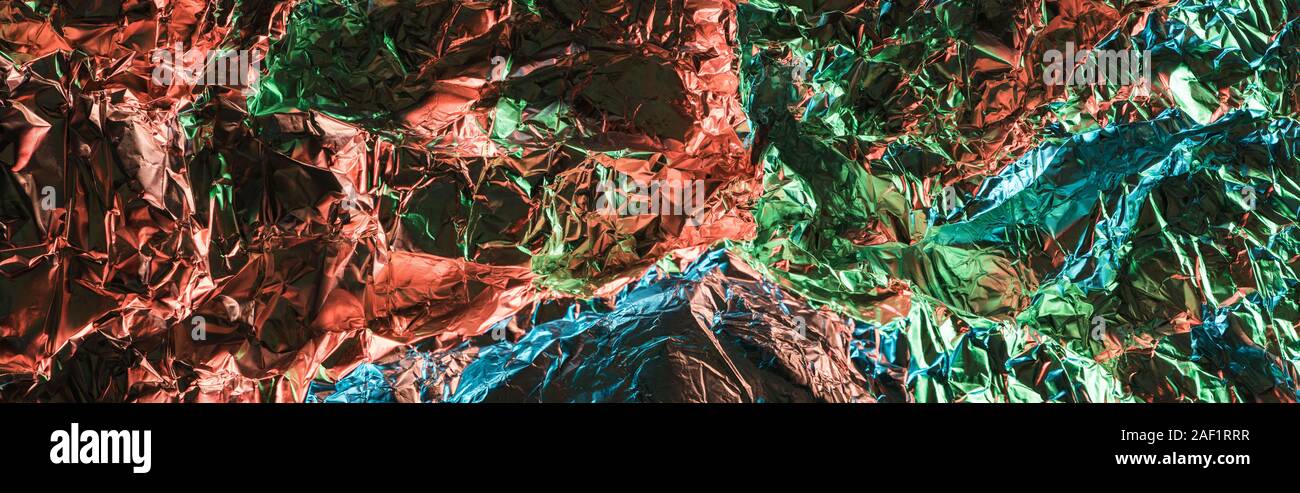 top view of glossy crumpled foil with colorful lighting reflection in ...