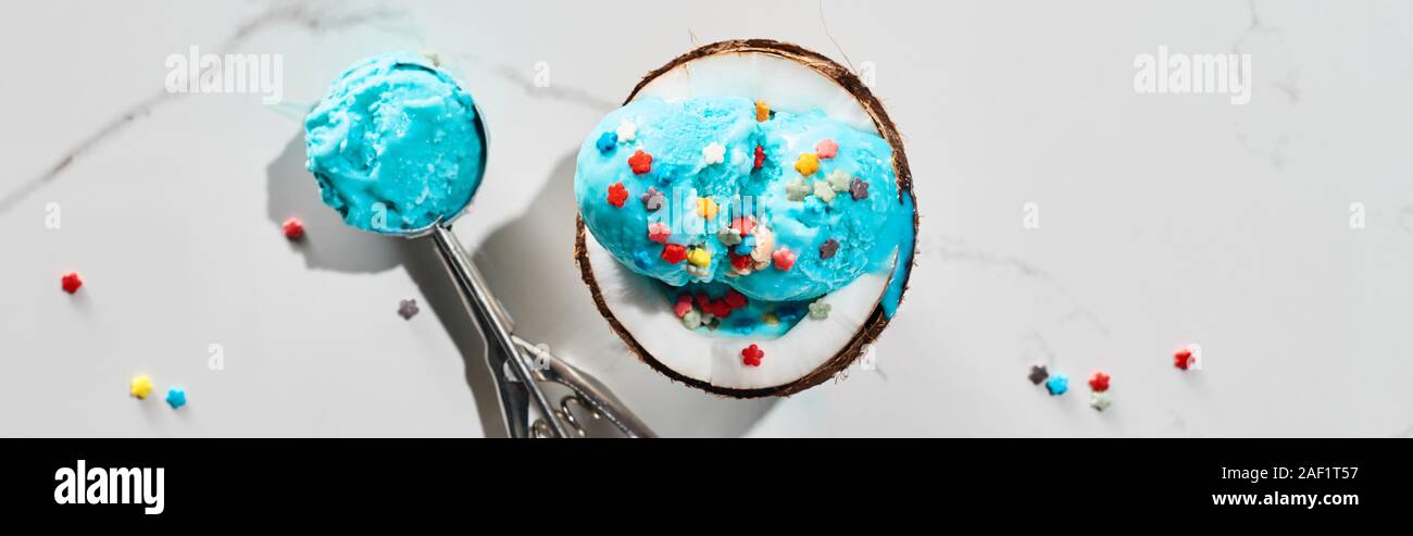 top view of delicious blue ice cream with sprinkles on coconut half and ...