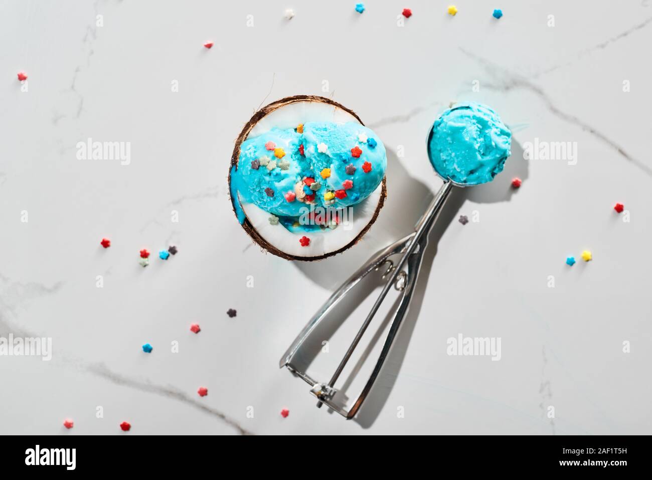top view of fresh blue ice cream with sprinkles on coconut half and in ...