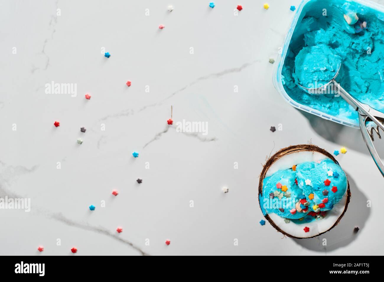 top view of delicious blue ice cream with sprinkles on coconut half and ...