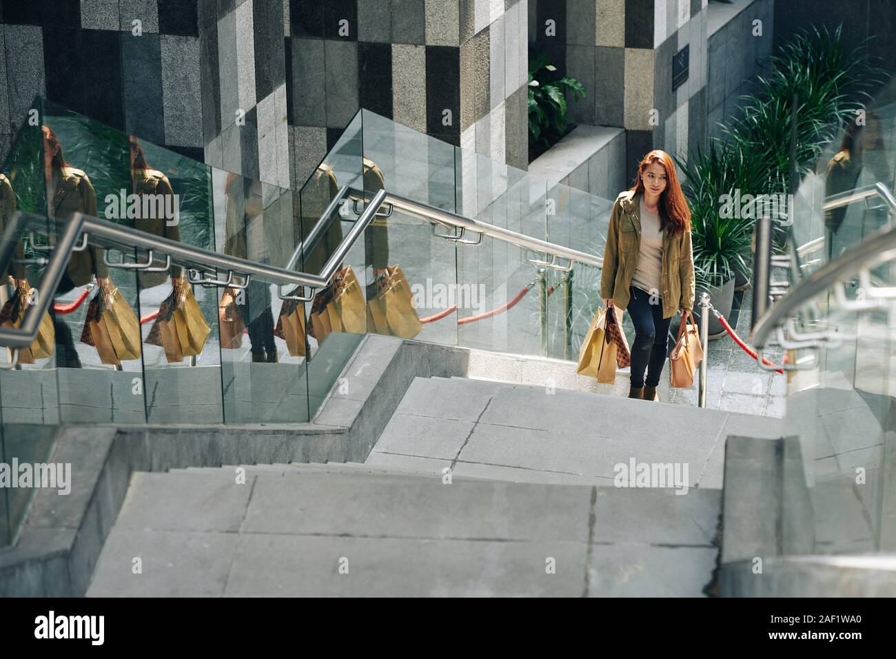 Pretty Vietnamese woman walking up the stairs with many paper-bags in ...