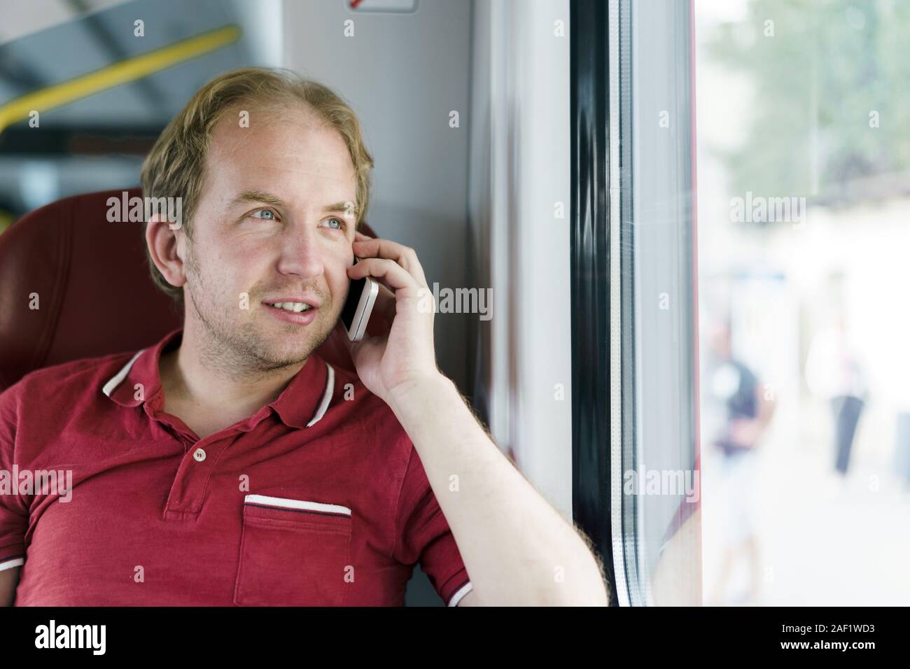 A smiling man in a suburban train speaking by phone and smiling Stock ...