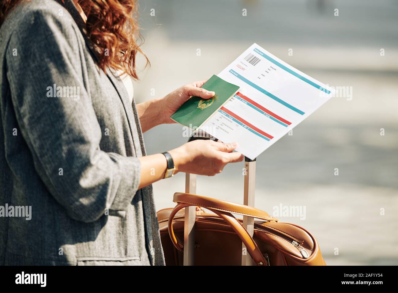Female passenger checking information in her plane ticket when standing ...