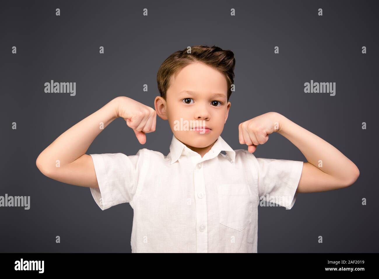 Little boy with raised hands showing his muscles Stock Photo - Alamy