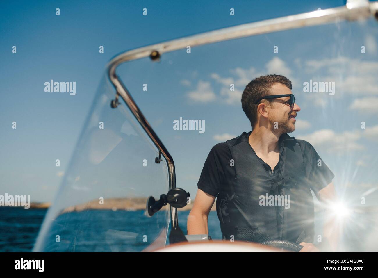 Man steering boat Stock Photo - Alamy