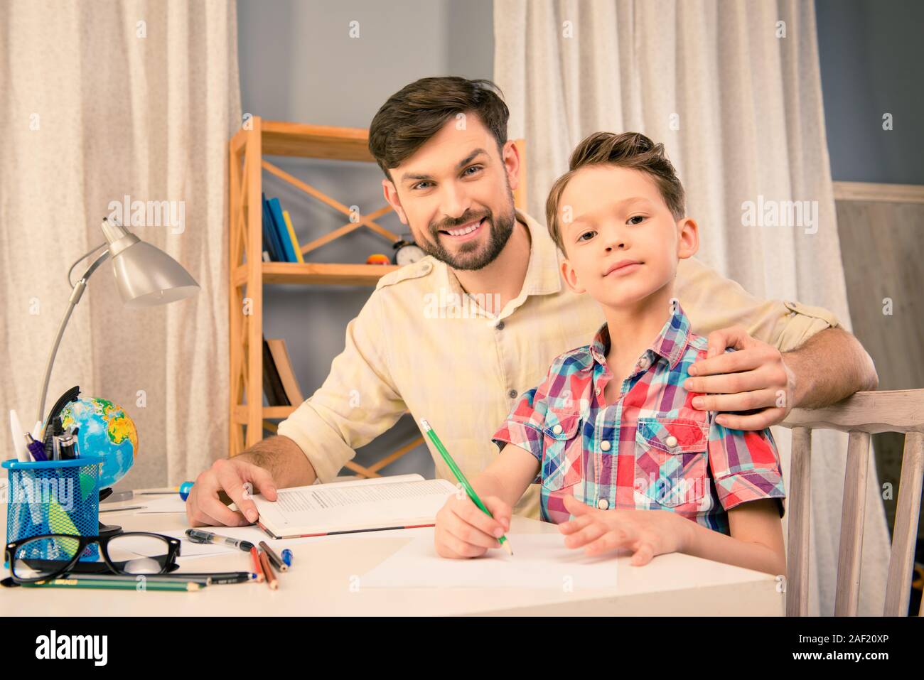 Portrait of happy young father helping his son with homework Stock ...