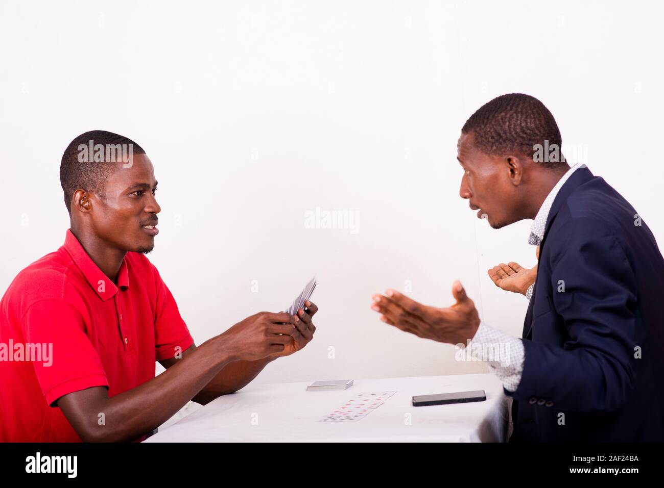 Young men playing cards at the game table, Young people having funny ...