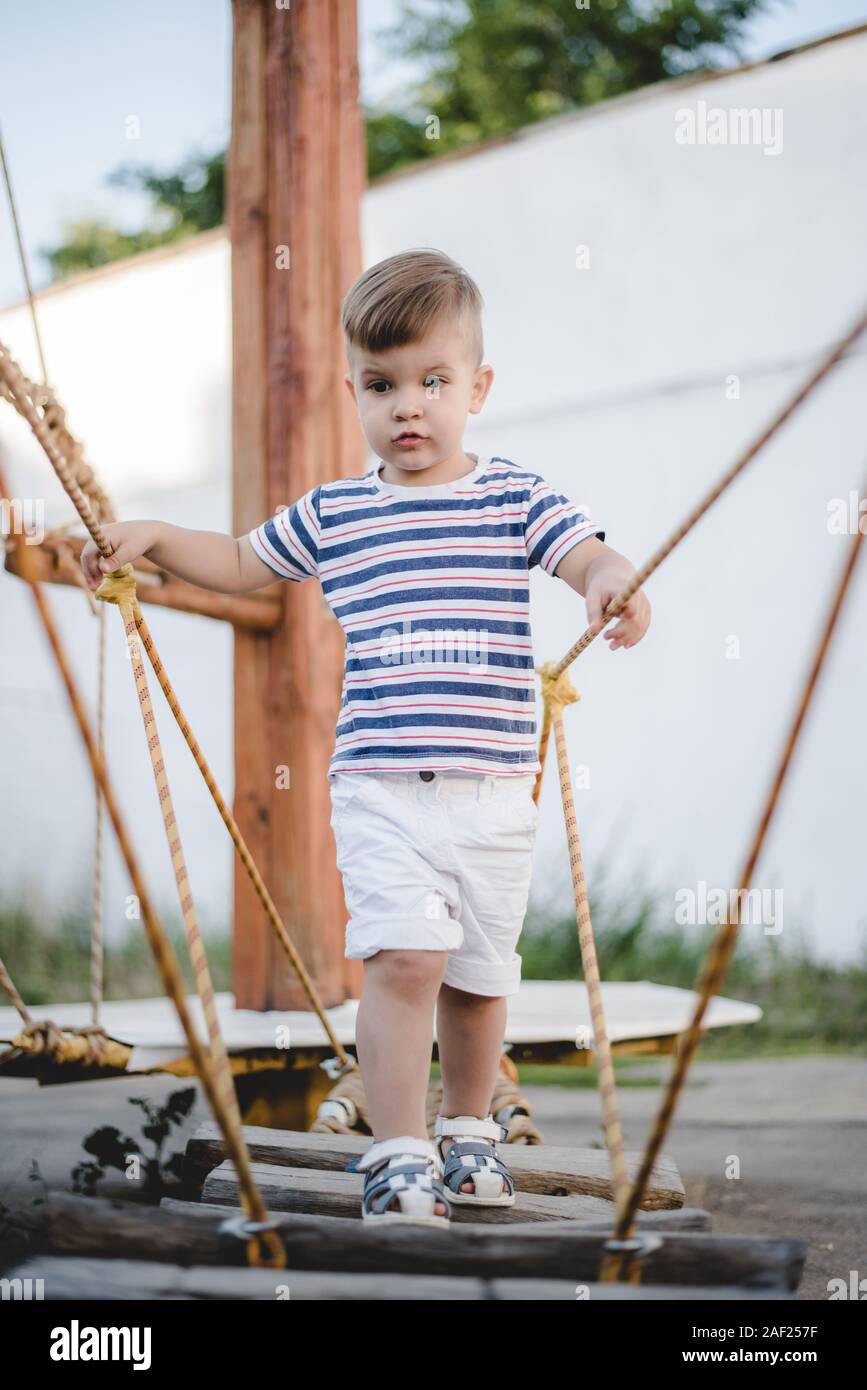 a little boy plays in a rope town, and overcomes an obstacle Stock ...