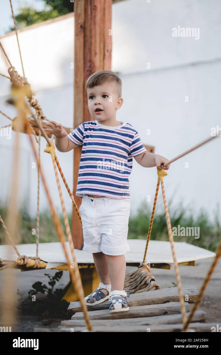 a little boy plays in a rope town, and overcomes an obstacle Stock ...