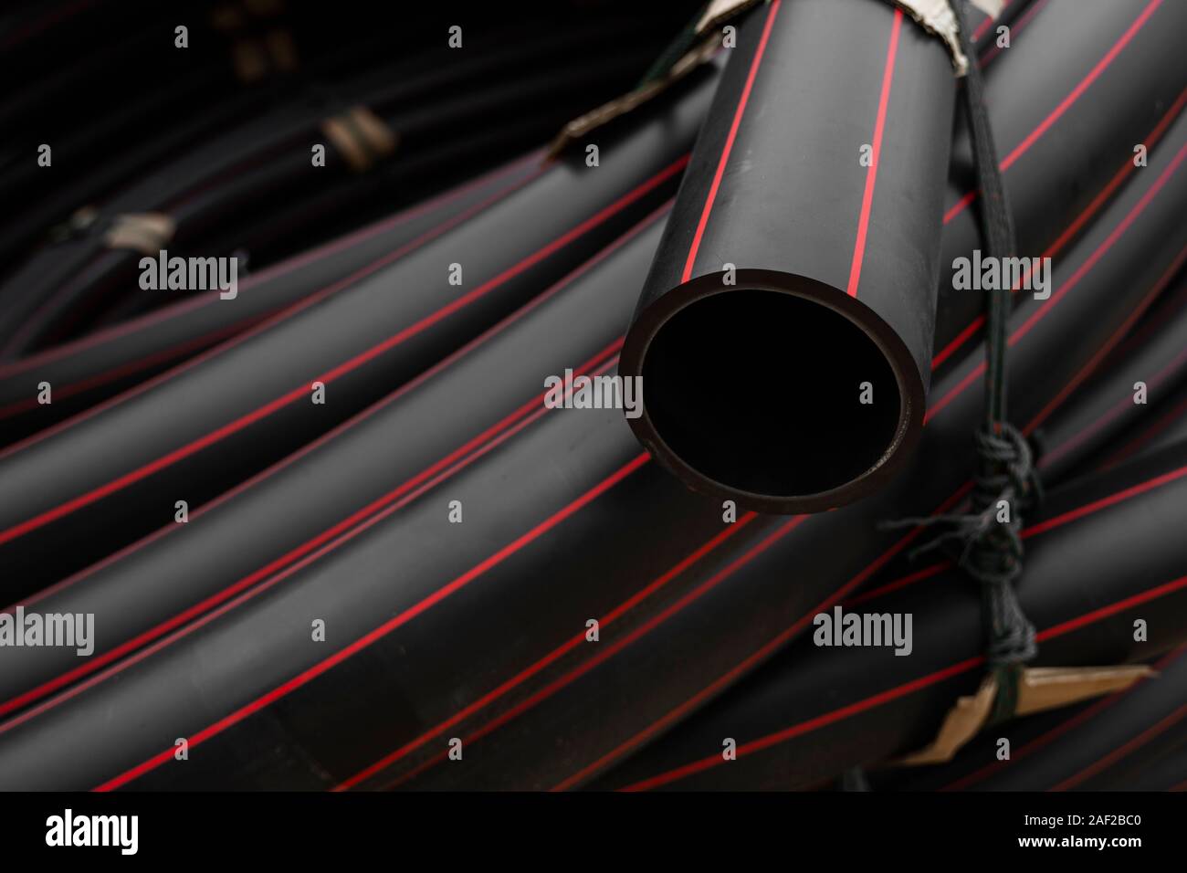Black rubber or plastic pipes with a red lines as a construction ...