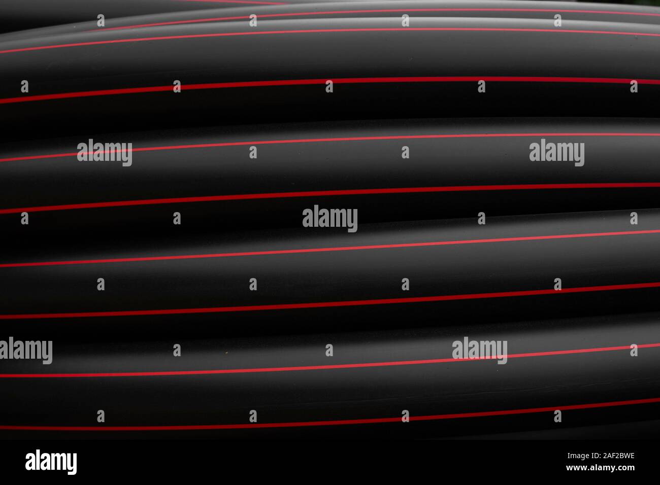 Black rubber or plastic pipes with a red lines as a construction ...