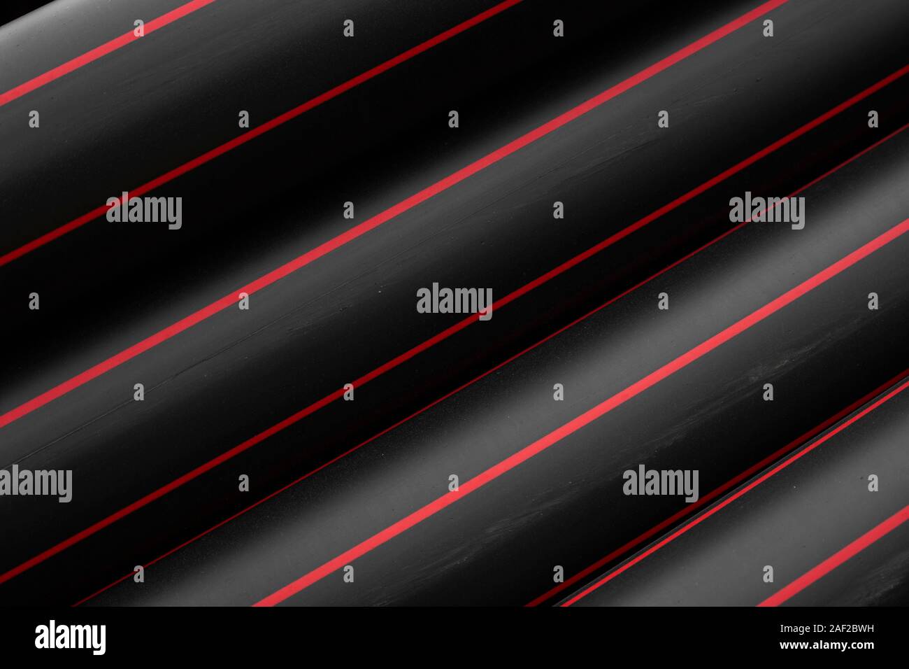 Black rubber or plastic pipes with a red lines as a construction ...