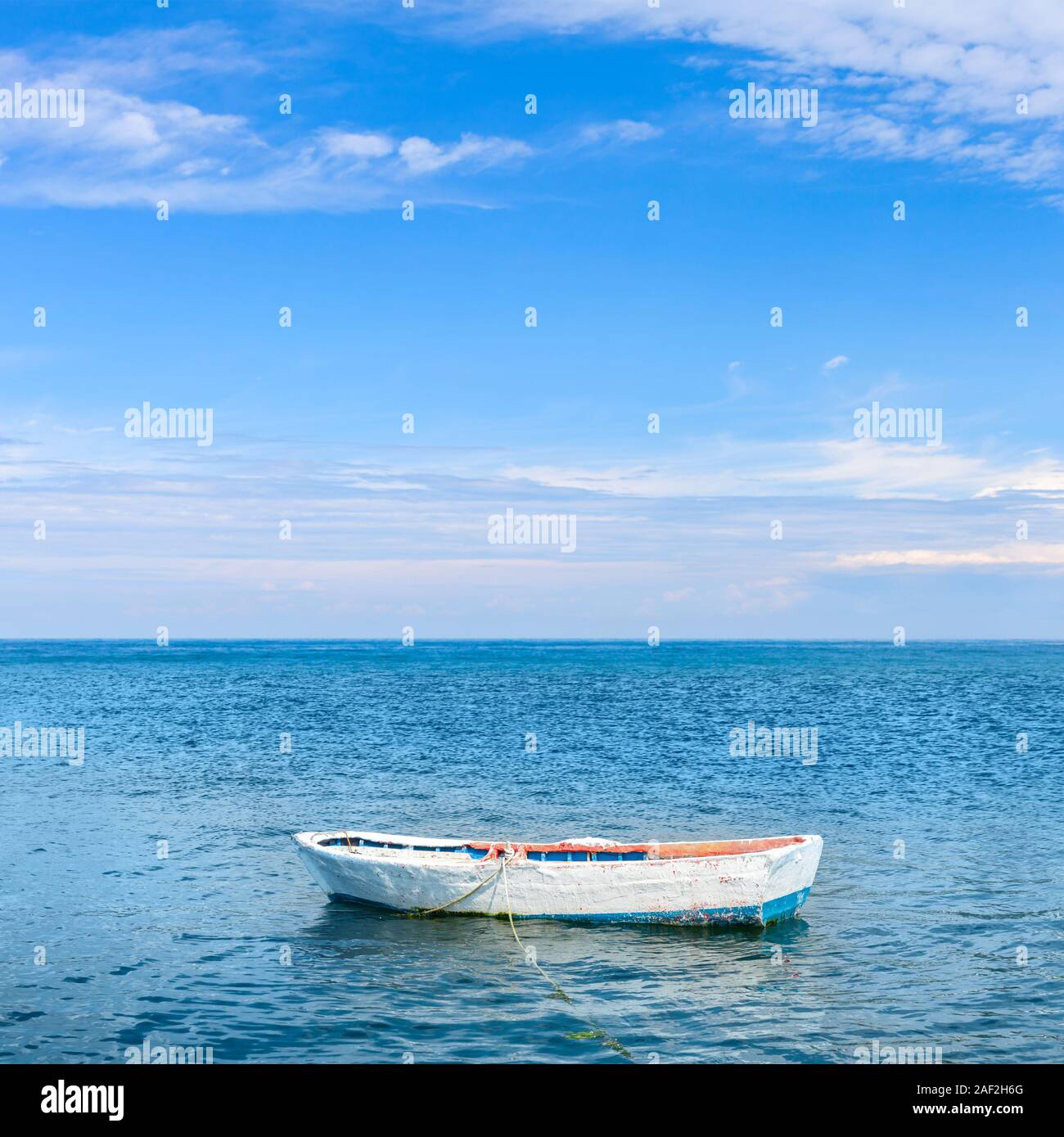 Small white wooden fishing boat. Square seascape with blue cloudy sky ...