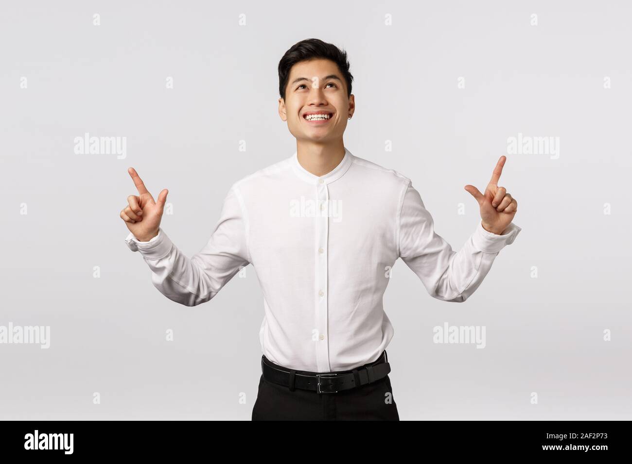 Cheerful impressed, dreamy handsome asian guy in shirt, black pants ...