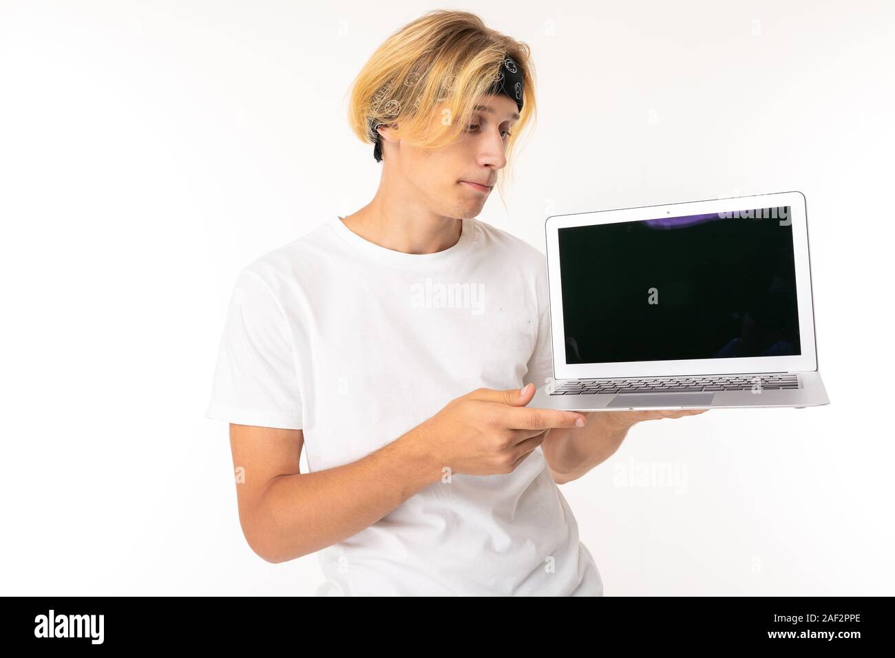 Stylish caucasian blonde man shows laptop isolated on white background ...