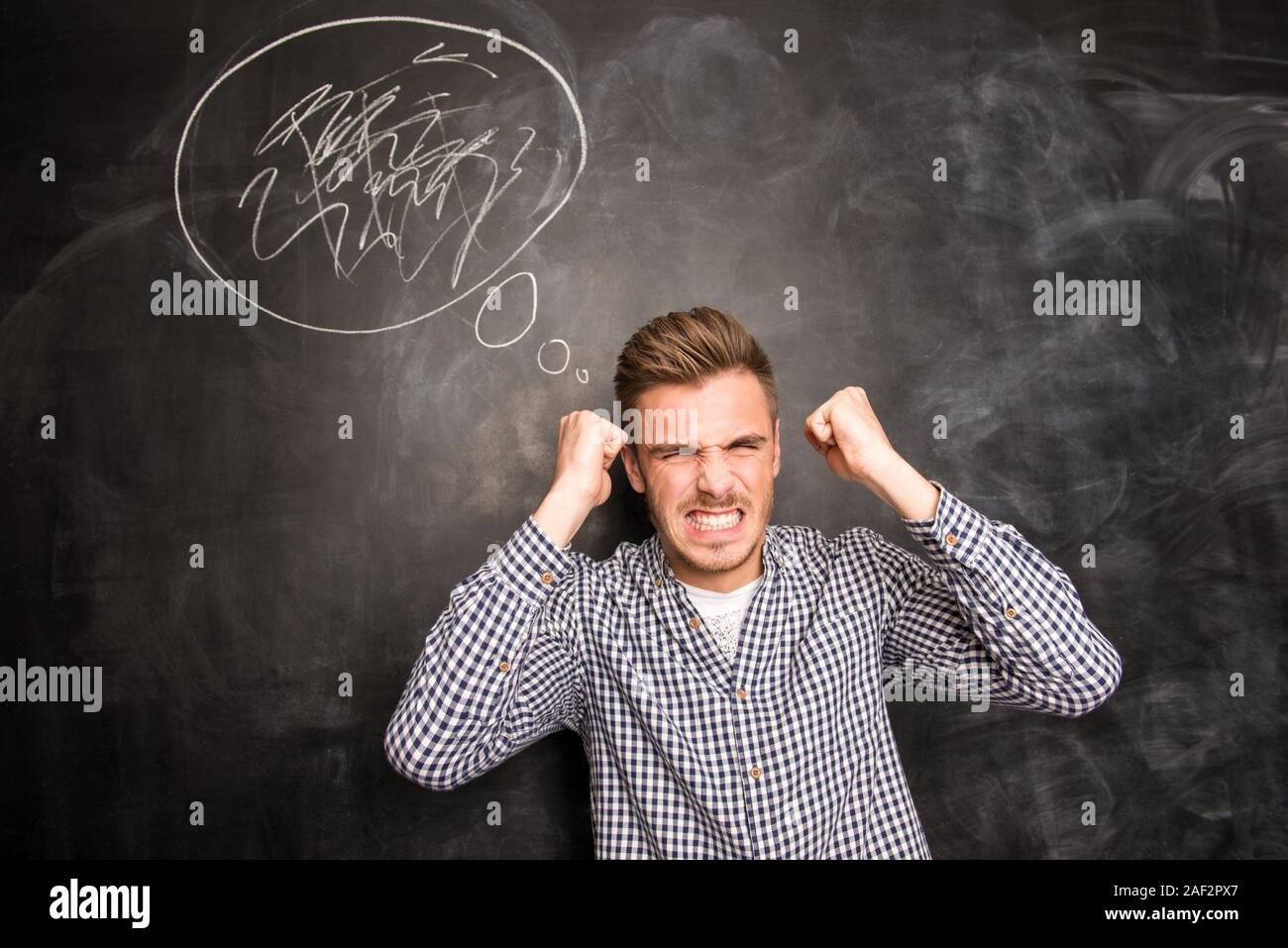 Angry young man in rage standing against the background of chalkboard ...