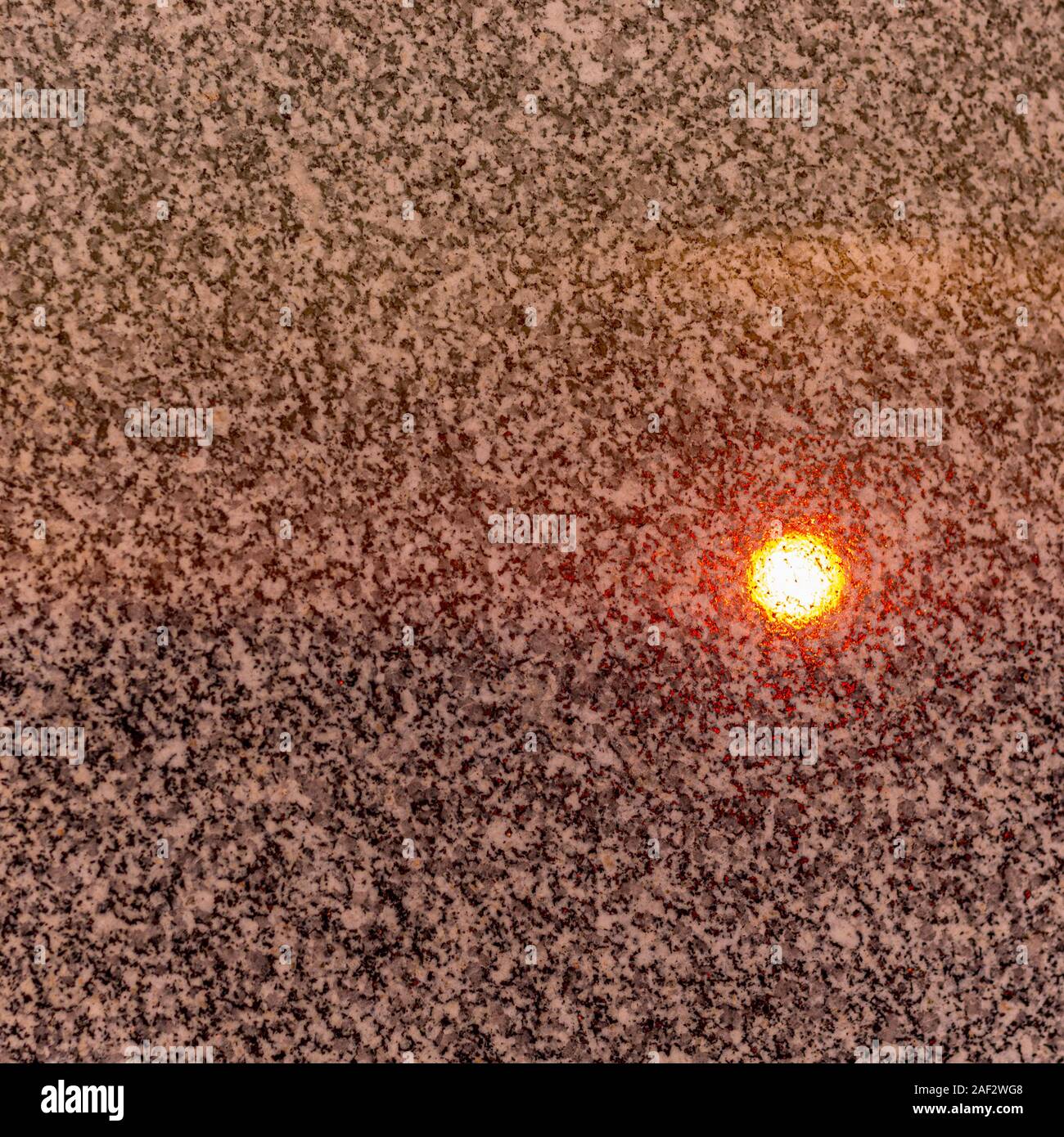 The setting sun reflected in a polished marble tombstone in a Japanese ...