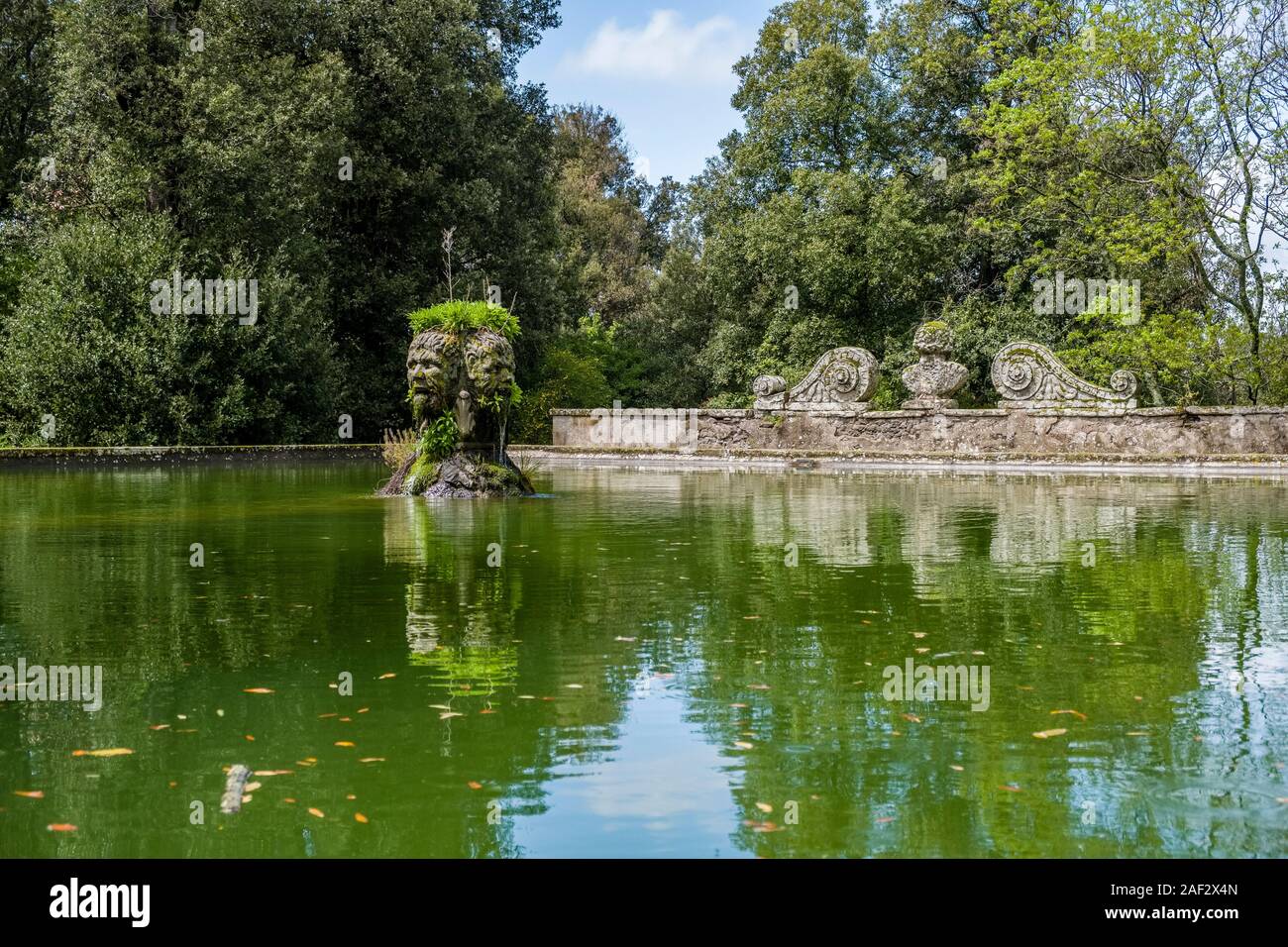 The overgrown sculpture of four heads, being a fountain in the middle ...