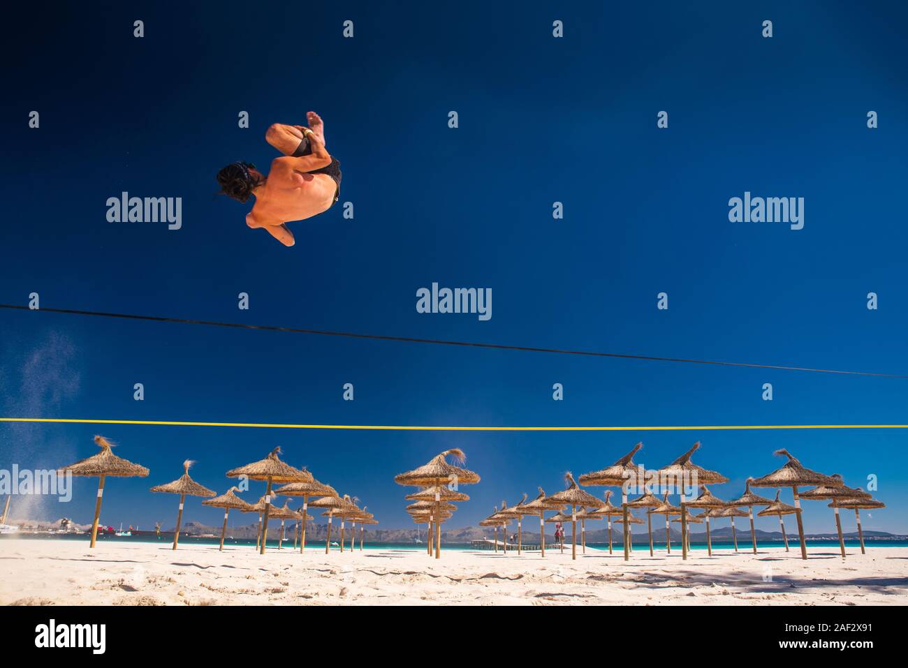 Man jumping on slackline on the summer tropical beach. White sand and ...