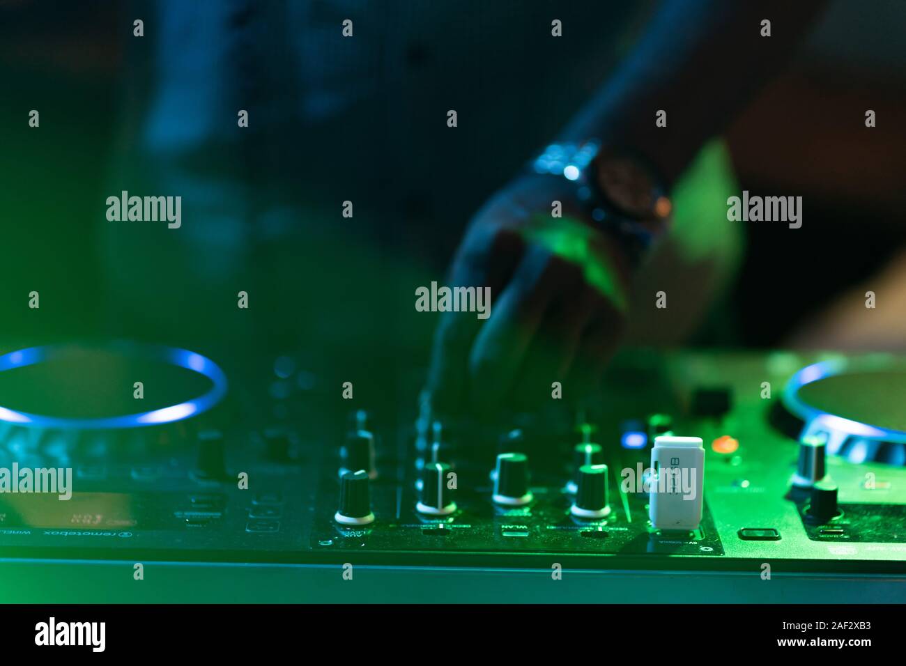 club dj plays music on stage in nightclub.Hand of disc jockey adjusting ...