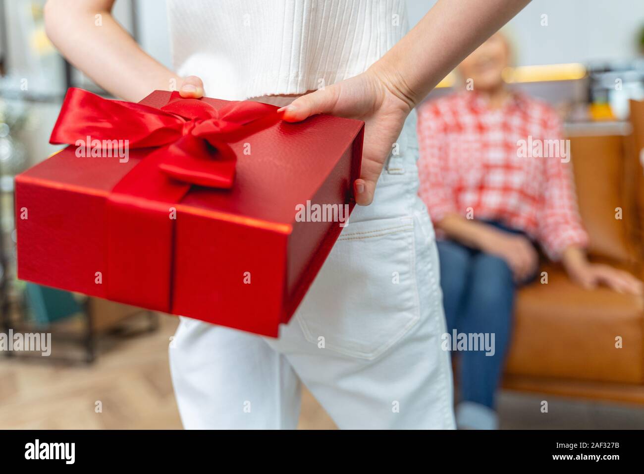 Female hiding a present behind her back Stock Photo - Alamy