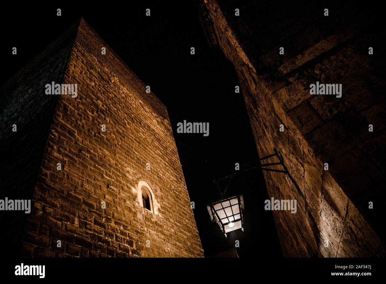 Tall stone tower illuminated at night by an ancient lamppost, in the ...
