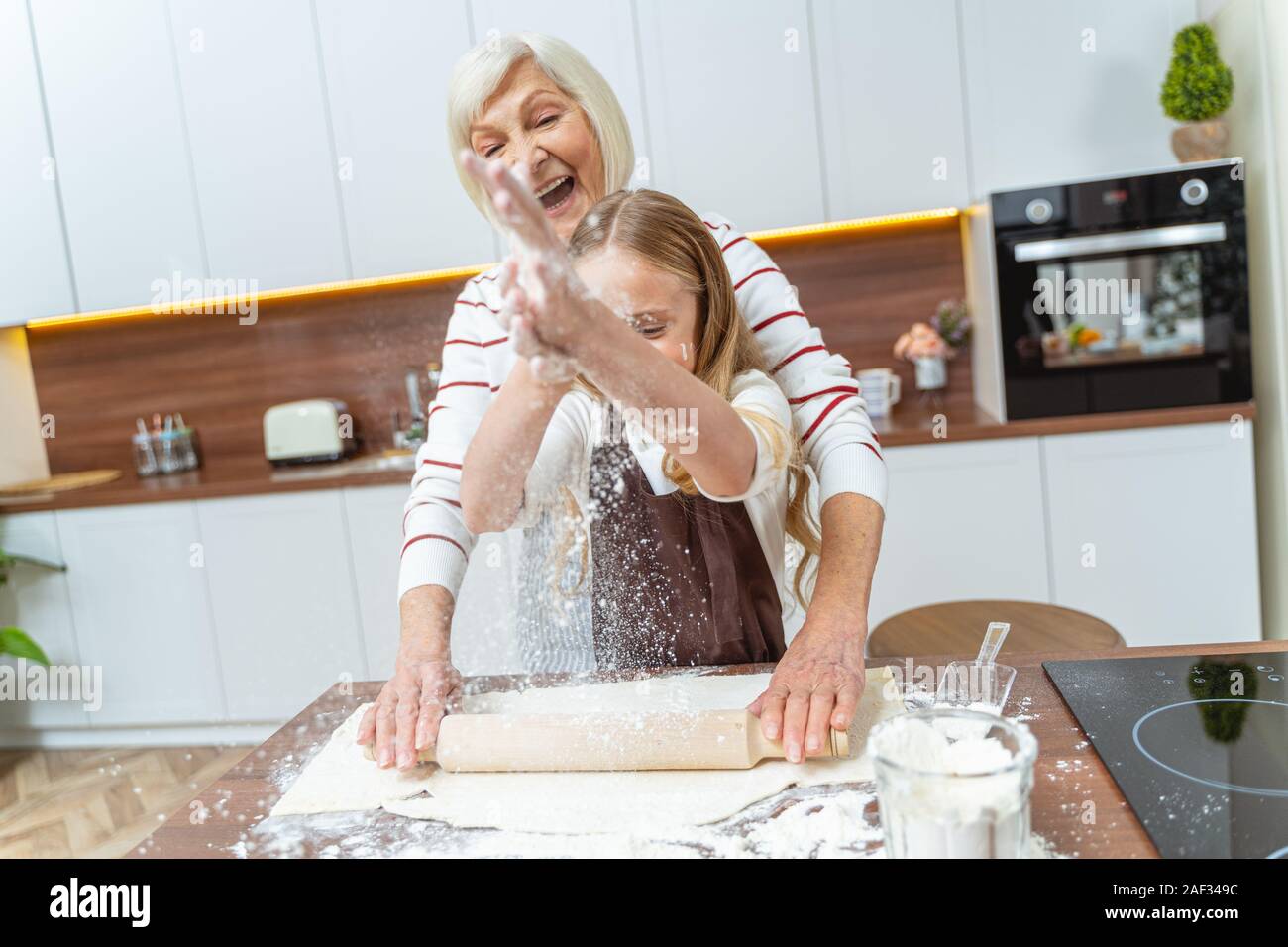 Young female baker sprinkling flour over the dough Stock Photo - Alamy
