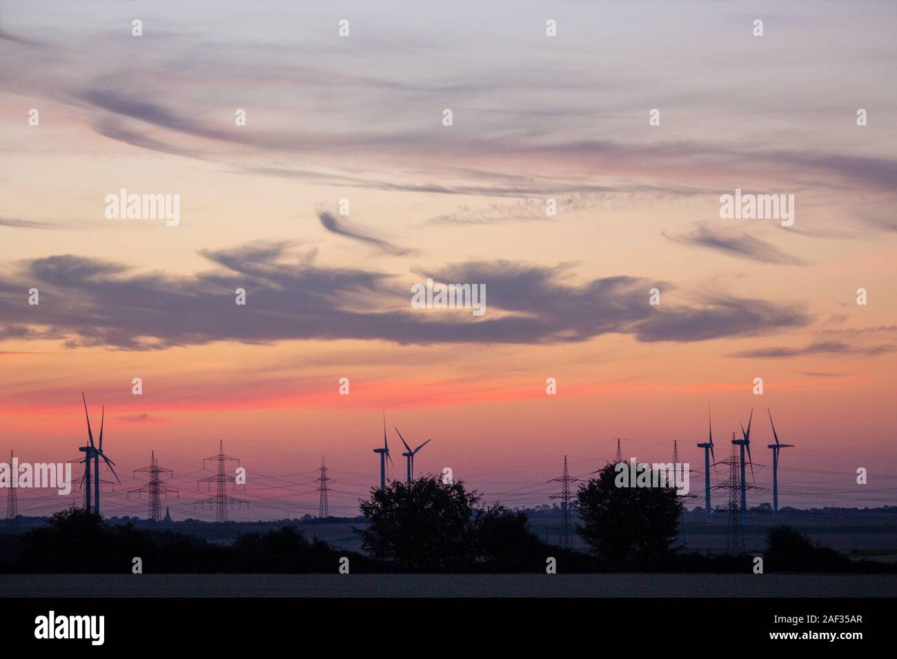 Wind farm with electricity pylons at dusk and red cloud sky Stock Photo ...