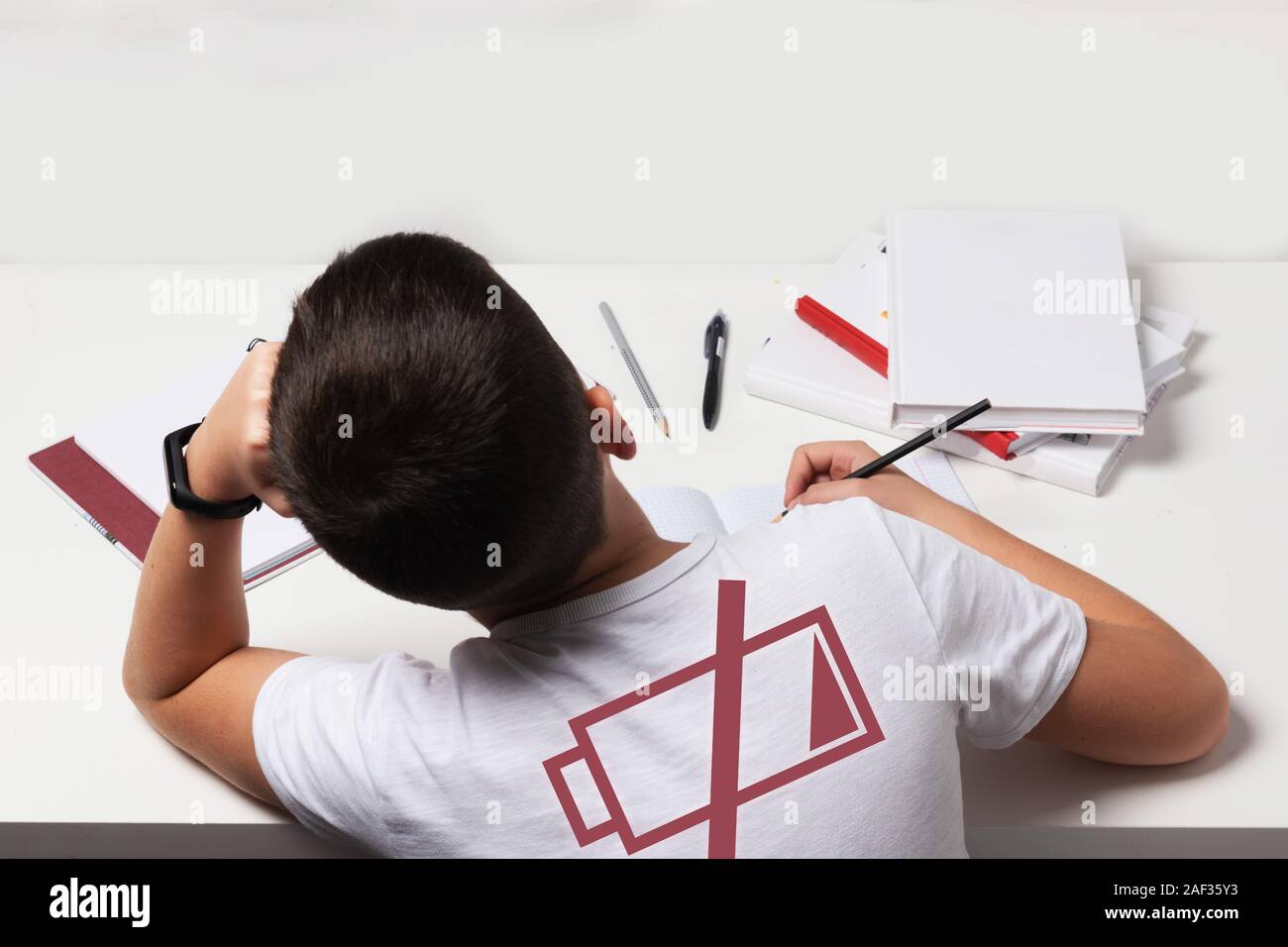 Bored and tired boy doing homework on white desk in his room. Schoolboy ...