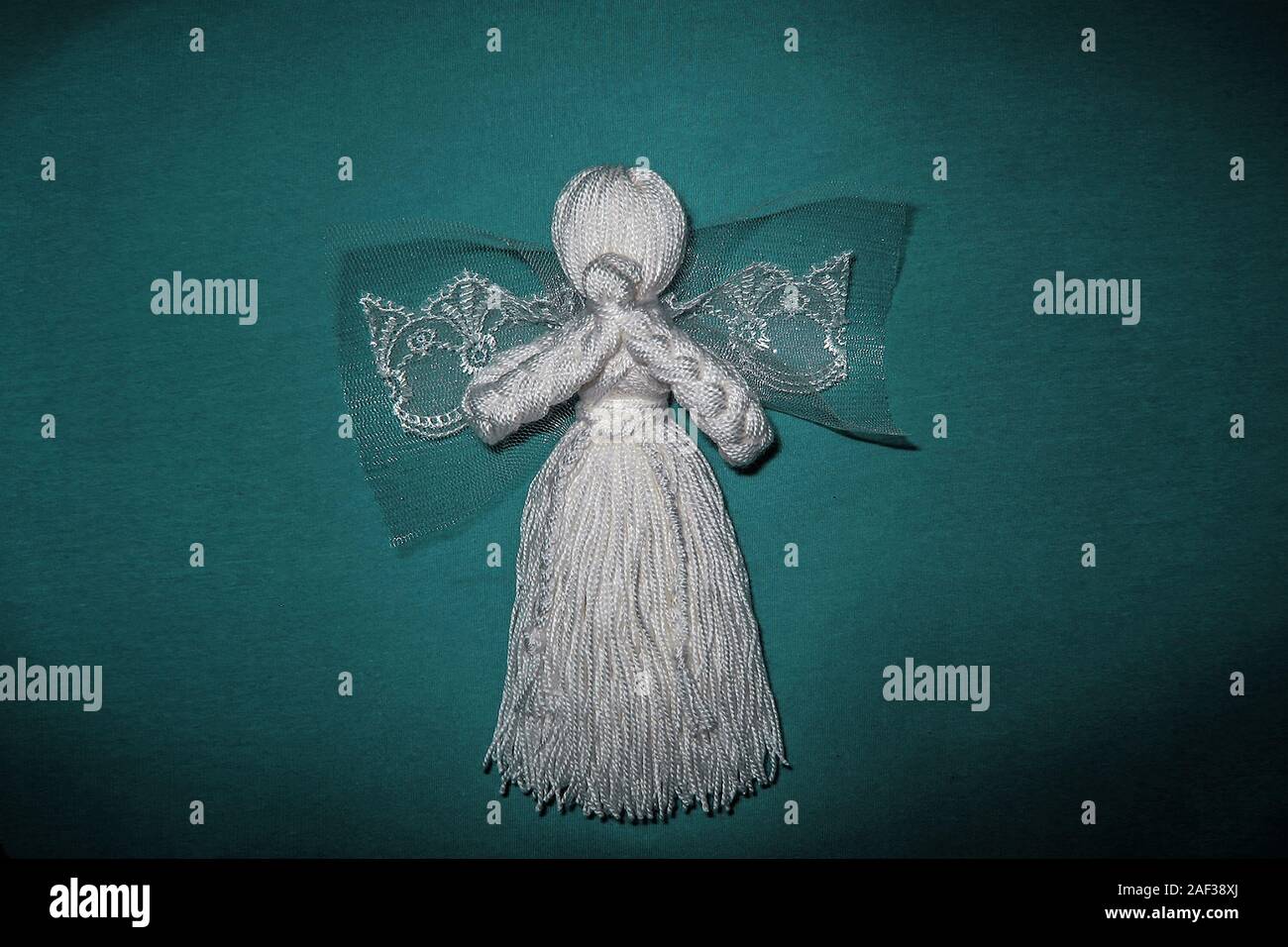 White angel with wings on cyan background. Prayed thread doll as a ...