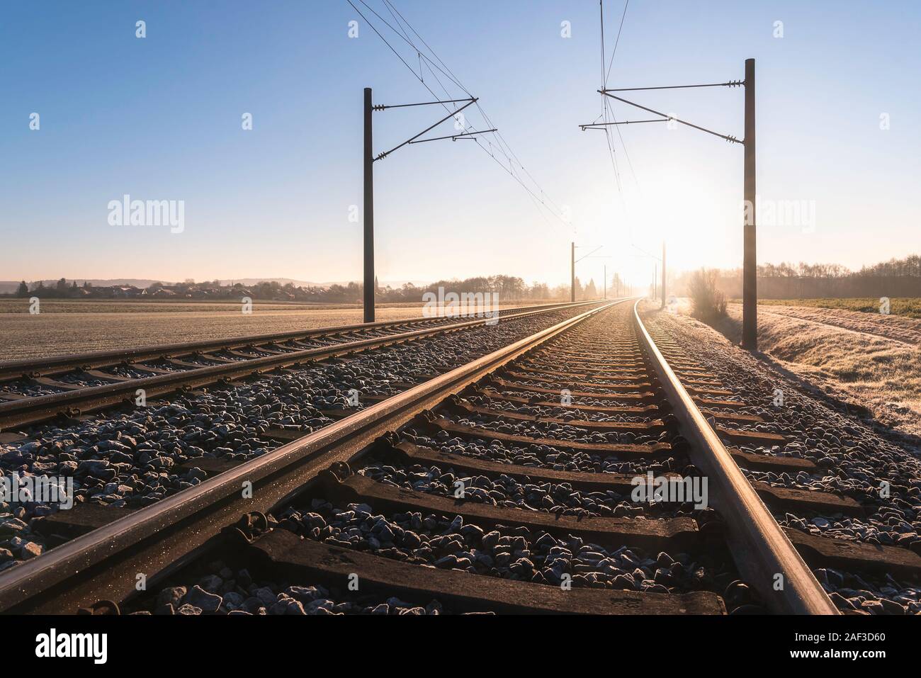 Railway tracks on a winter morning, frosted nature and bright sun ...
