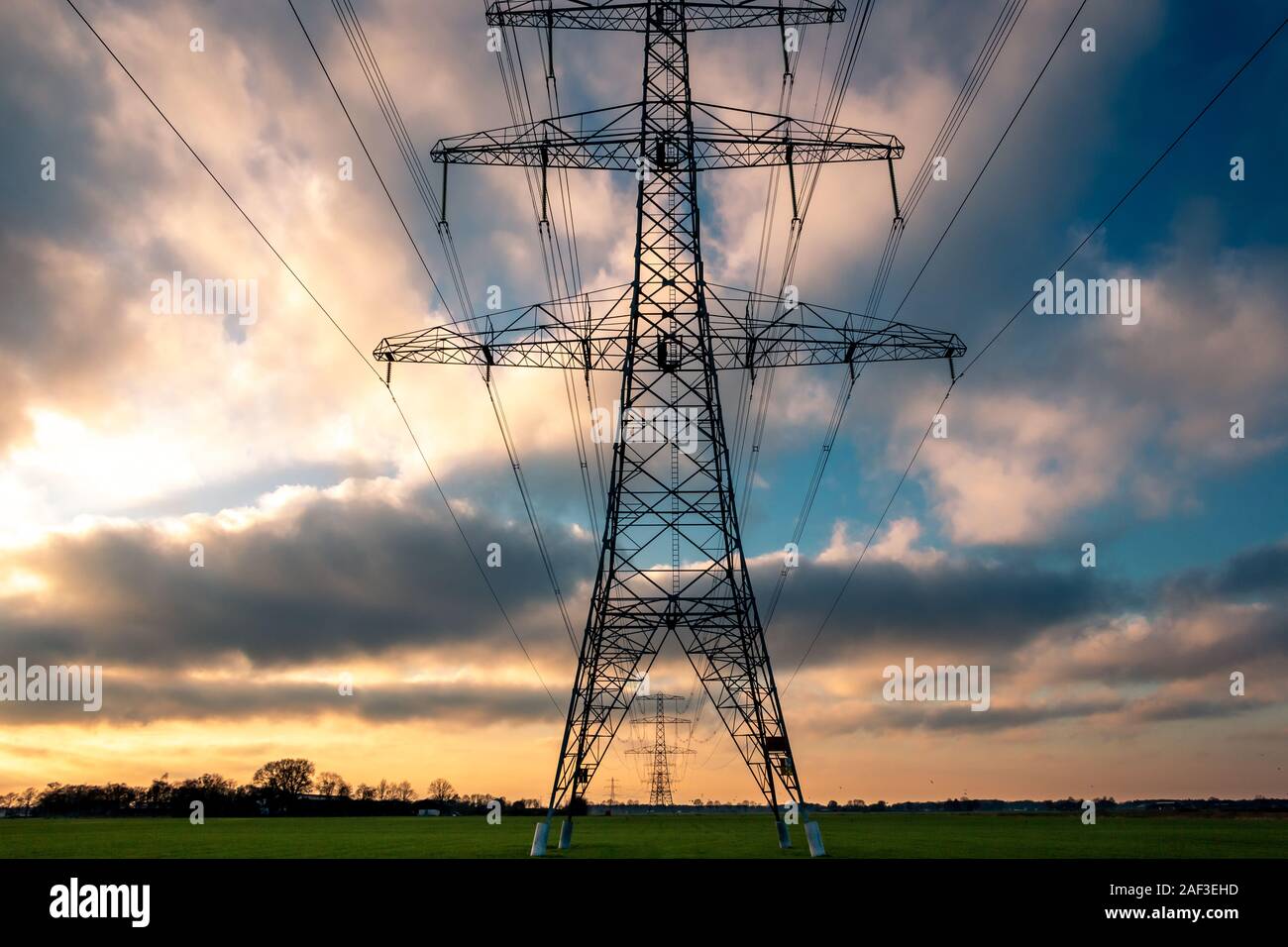 High voltage pylons in a beautiful landscape with colorful clouds in ...