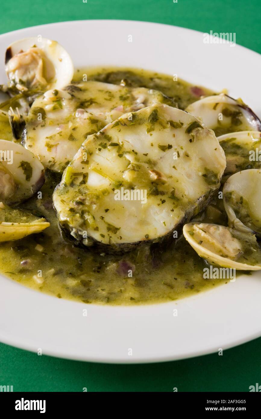 Hake fish and clams with green sauce on green background. Typical ...