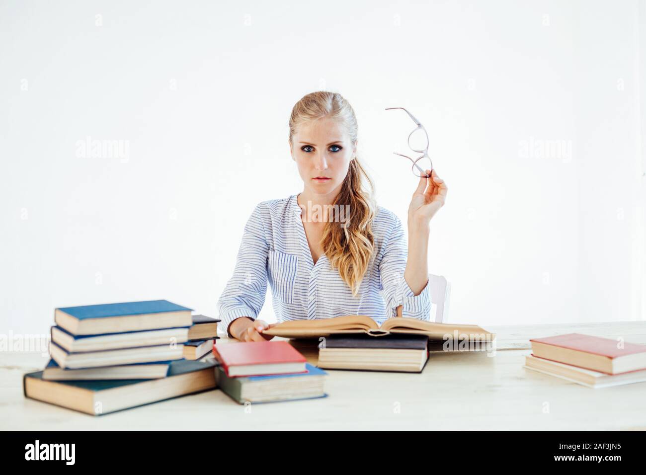 female teacher sitting at a table of many books Office Stock Photo - Alamy