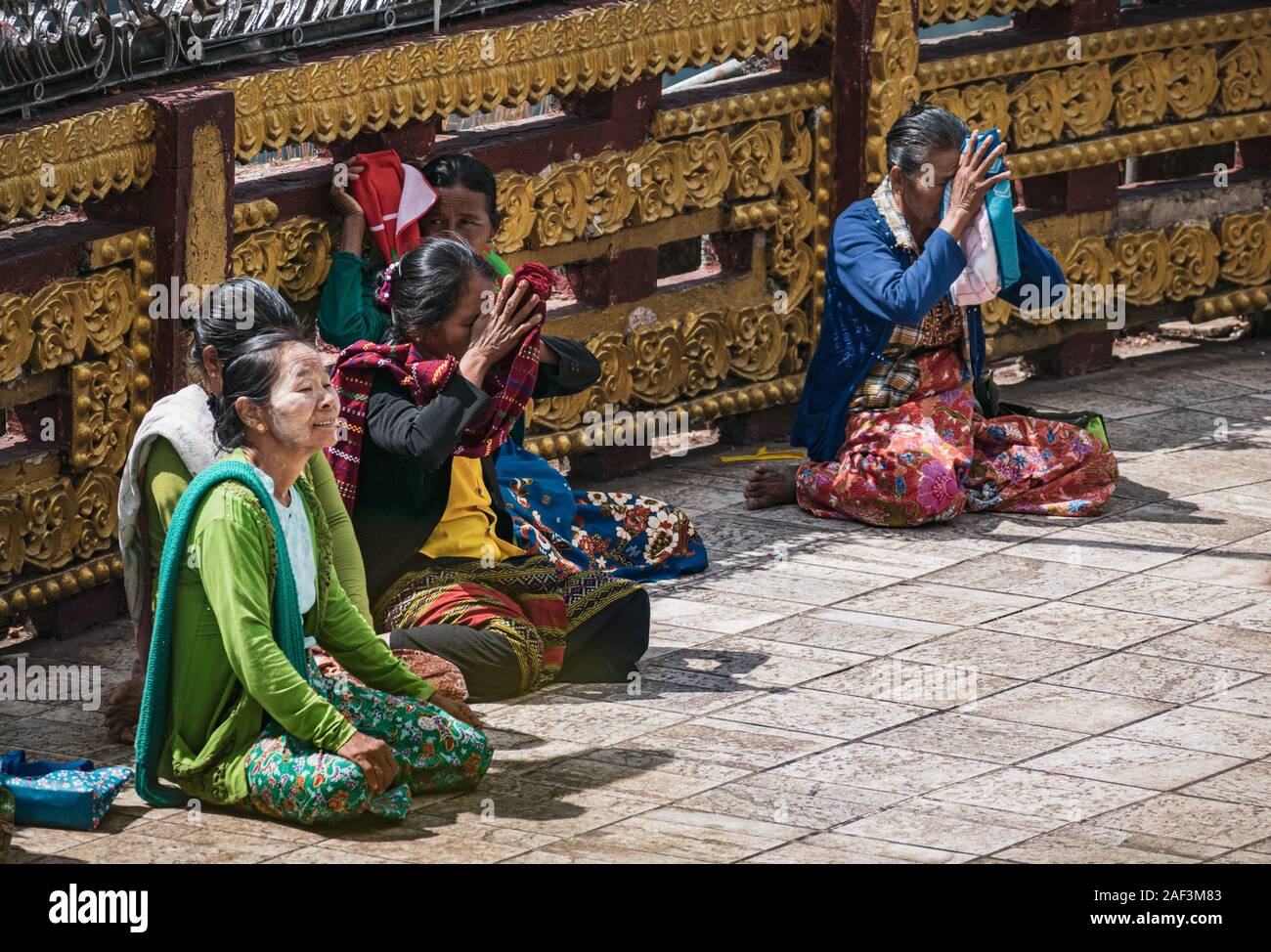 Burmese women in traditional outfits and faces painted with thanaka ...