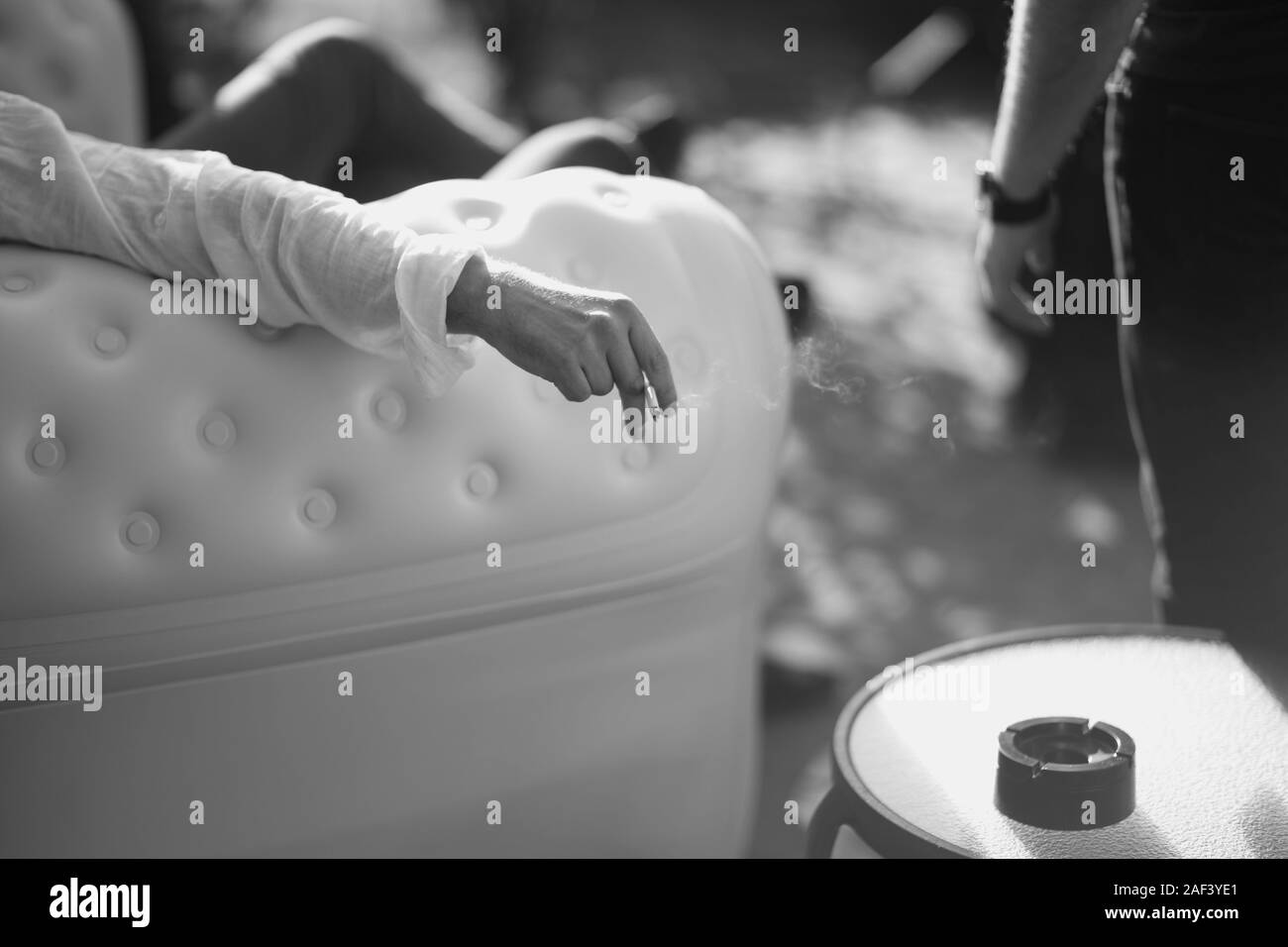 Hand of a man with a cigarette in a special smoking area of the ...