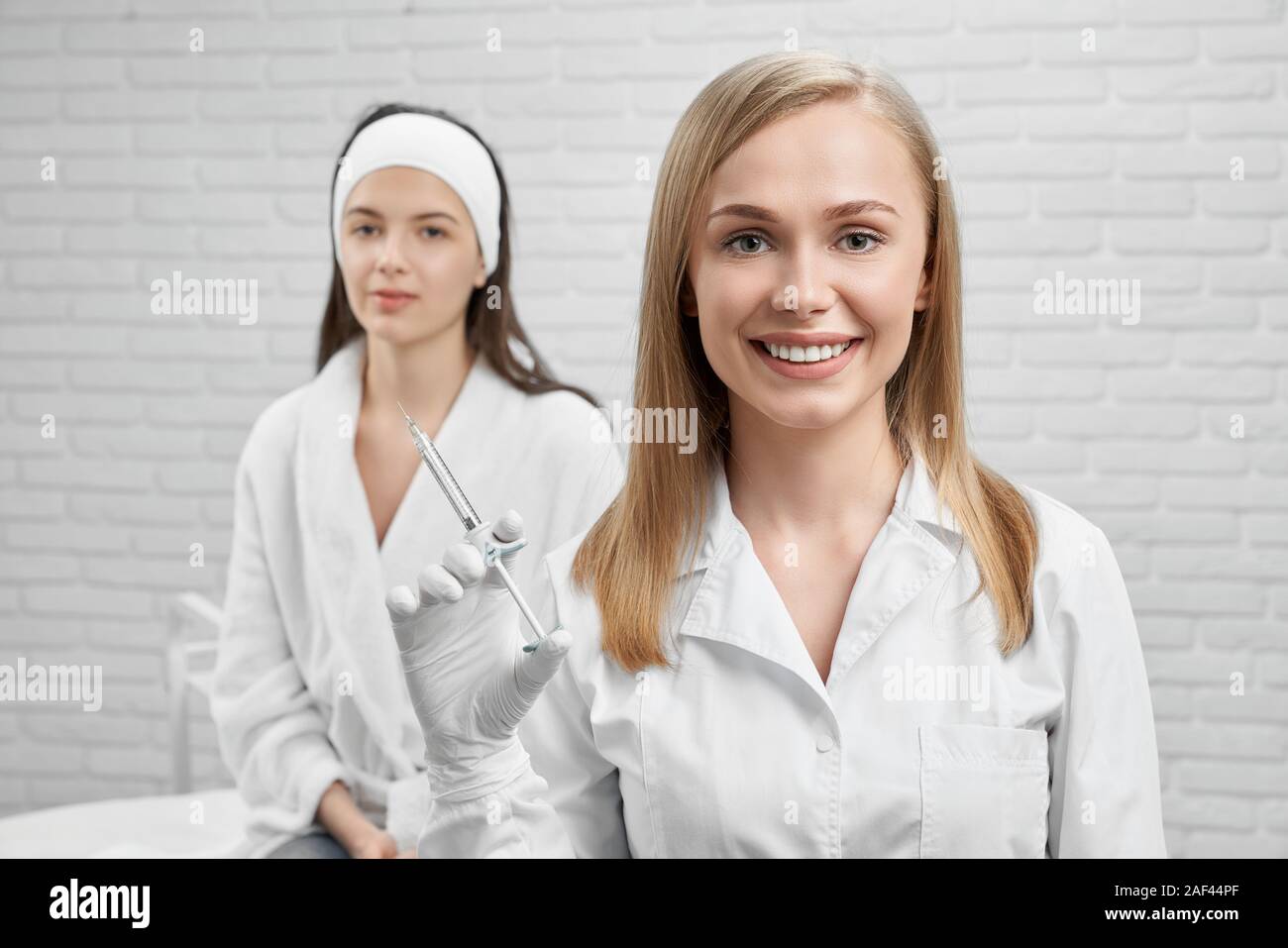 Front view of professional cosmetologist looking at camera, smiling and ...