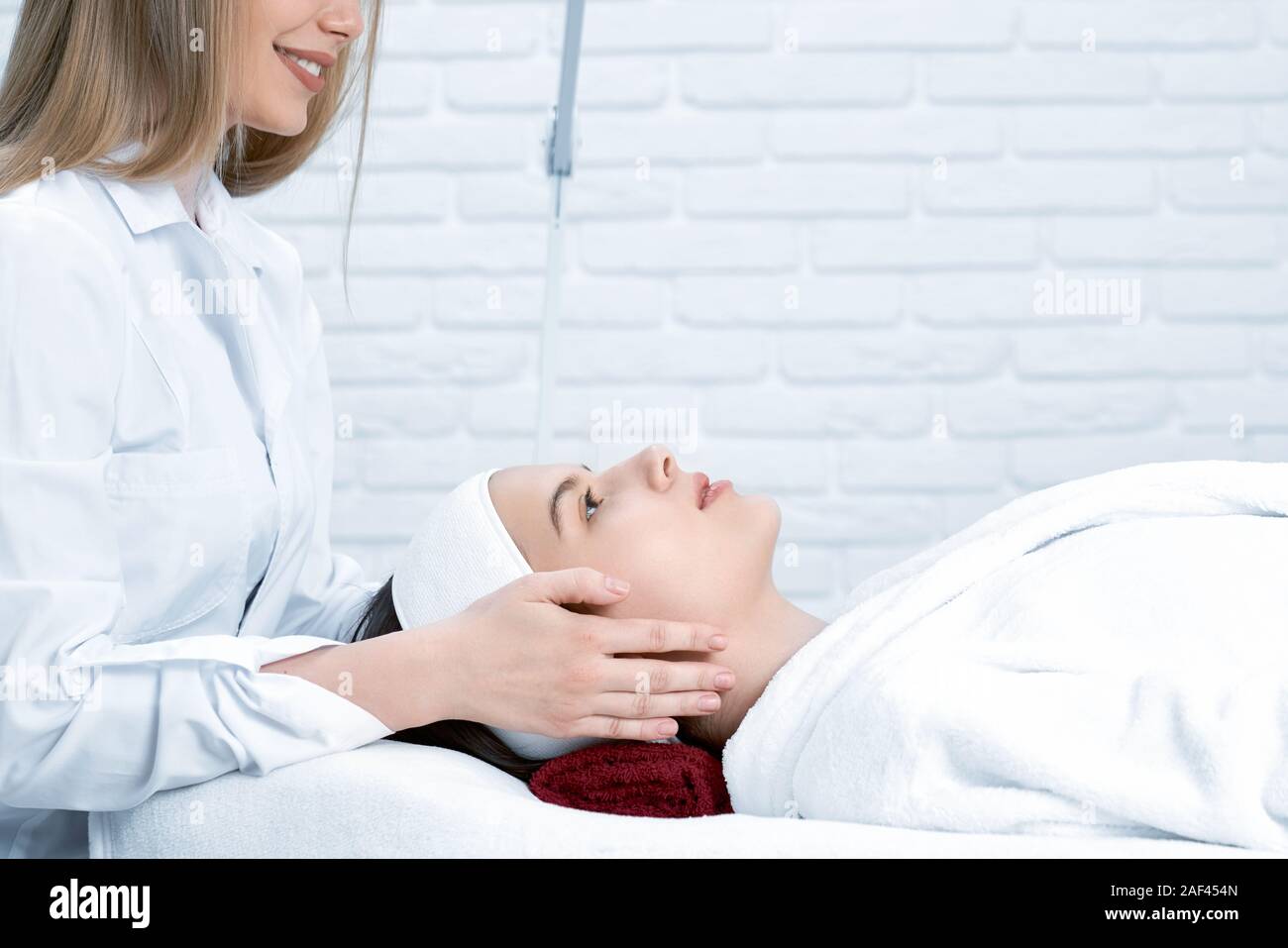 Side view of positive cosmetologist smiling and working while doing ...