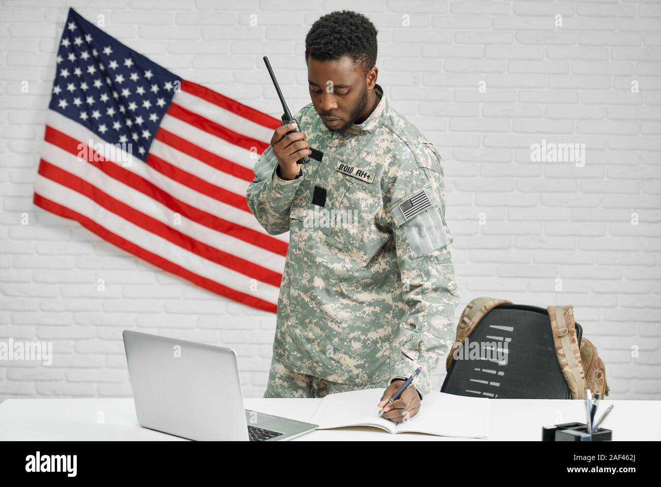 Worker of American army writing documents, using laptop and destination ...