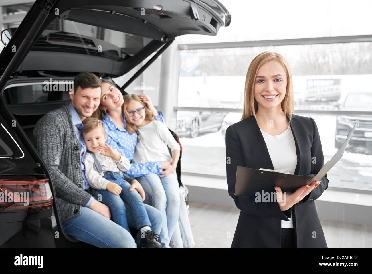 Front view of car seller looking at camera and posing in auto showroom ...