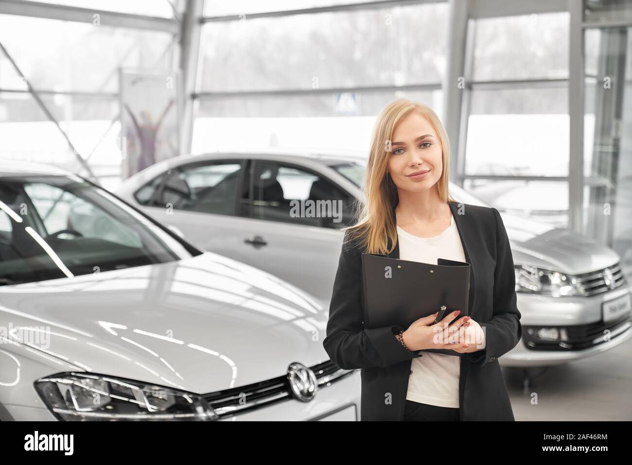 Professional car dealer wearing black smart suit keeping documents in ...
