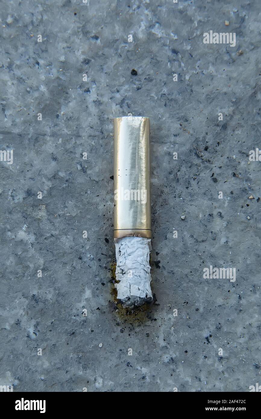 Cigarettes in gold . cigarette end on the pavement . Discarded ...