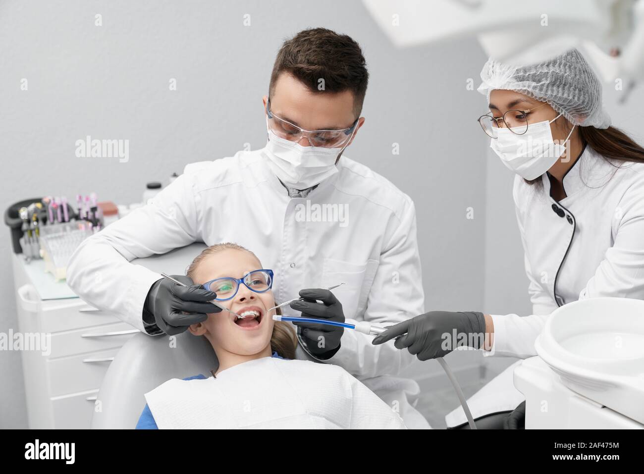 Process of teeth brushing in clinic. Male doctor and female assistant ...