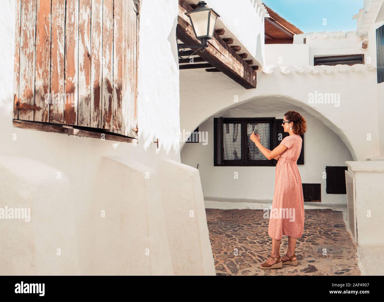 Tourist woman taking a photo in traditional fishing village of Binibeca ...