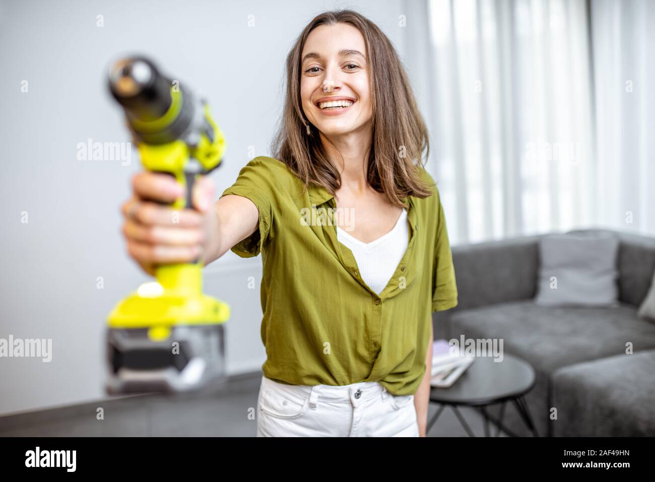 Portrait of a young and happy handywoman with cordless screwdriver at ...
