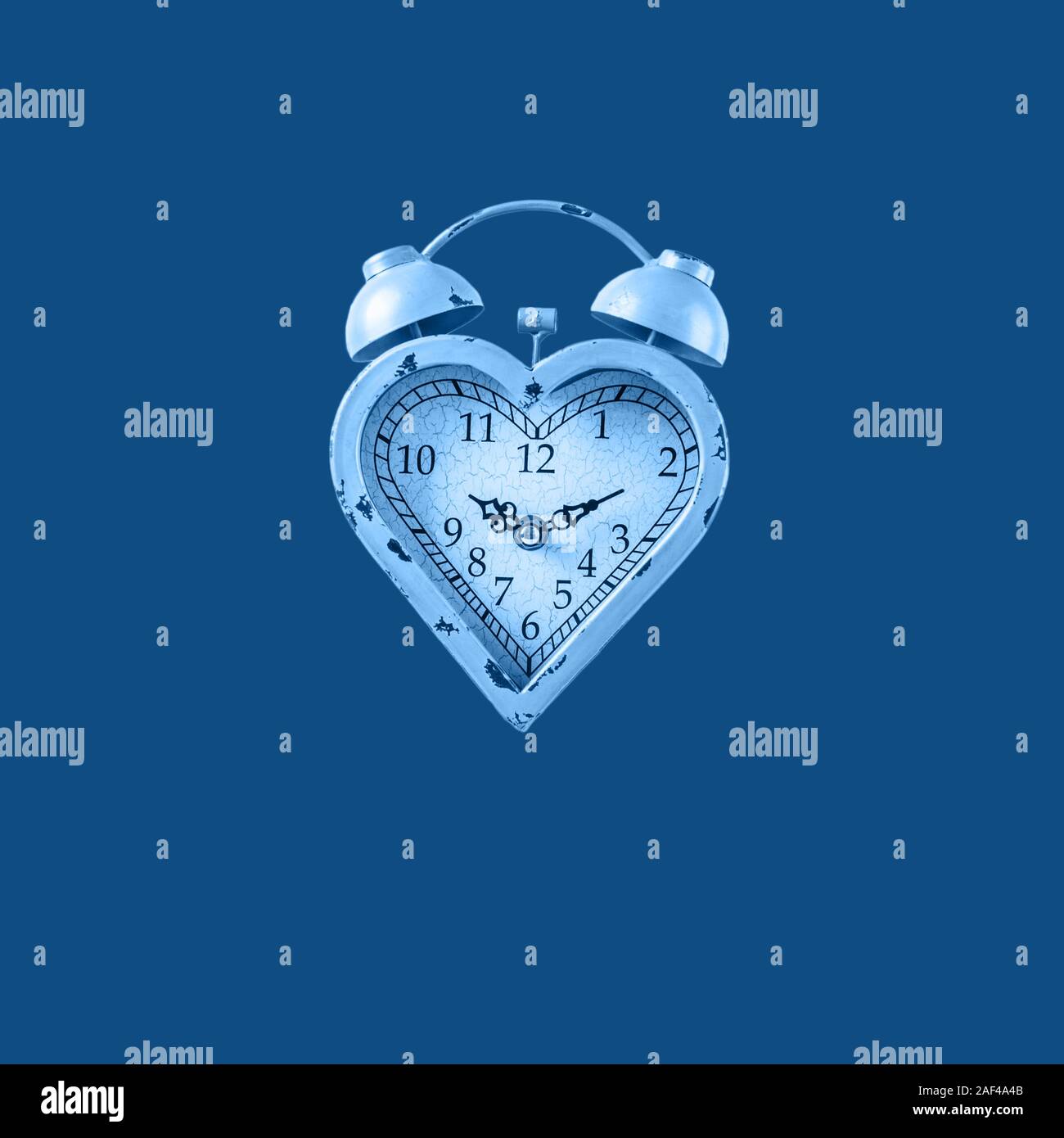 Heart shaped clock on solid background toned in classic blue ...