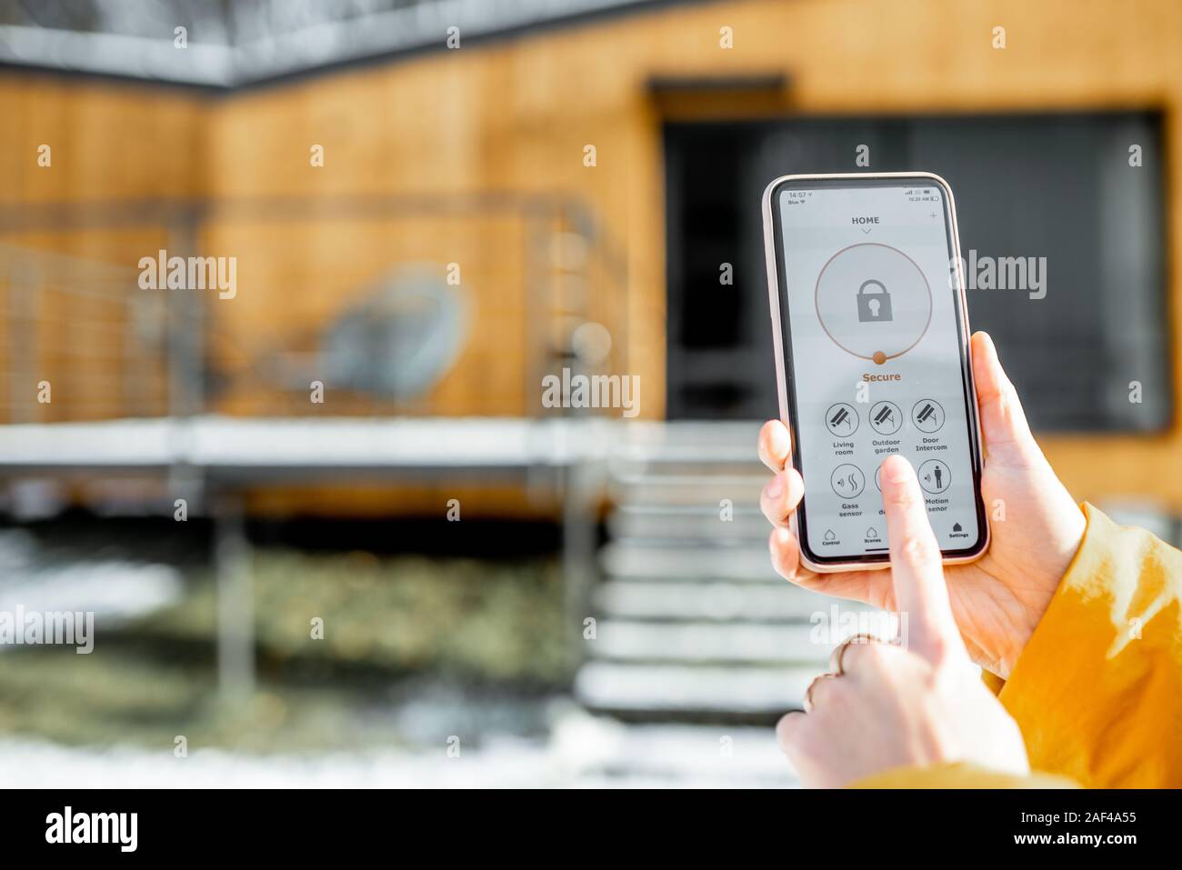 Holding phone with launched alarm app on the house background outdoors ...